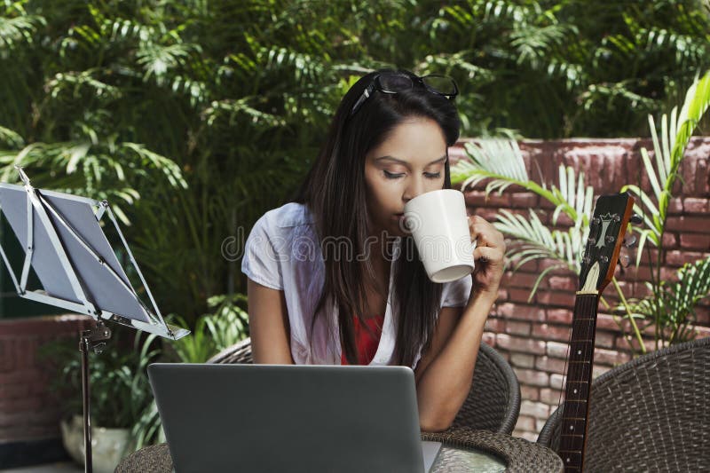 Woman Drinking Coffee and Using a Laptop Stock Image - Image of looking ...