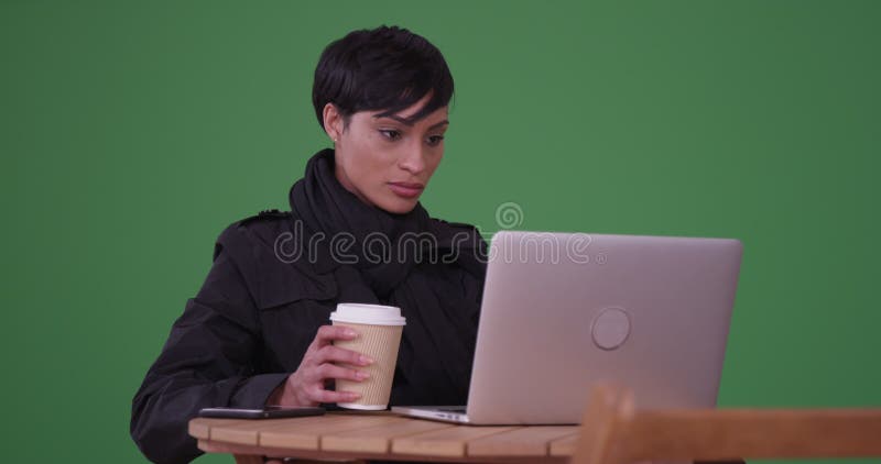 Woman Drinking Coffee Using Laptop Computer at a Caf_ Table on Green ...