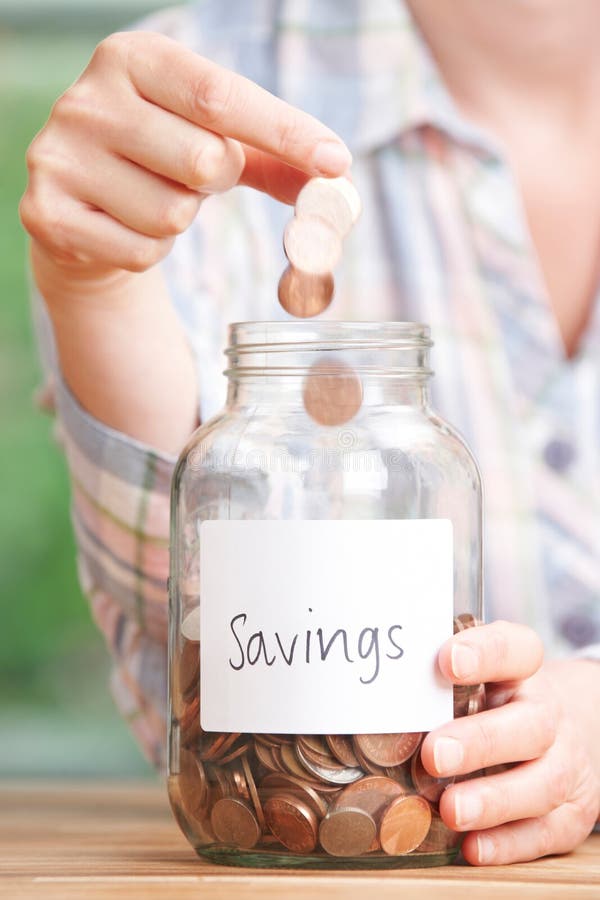 Woman Dropping Coins into Jar Labelled Savings Stock Image - Image of ...