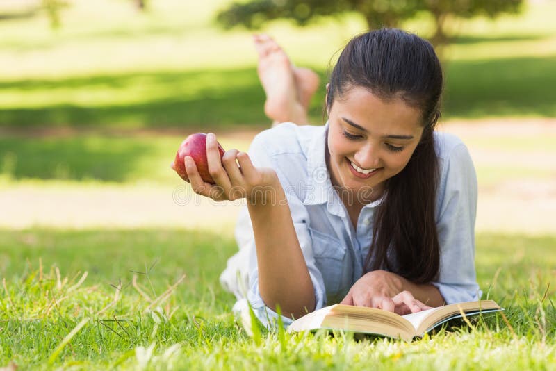 Woman Eating Apple while Reading a Book in Park Stock Image - Image of ...