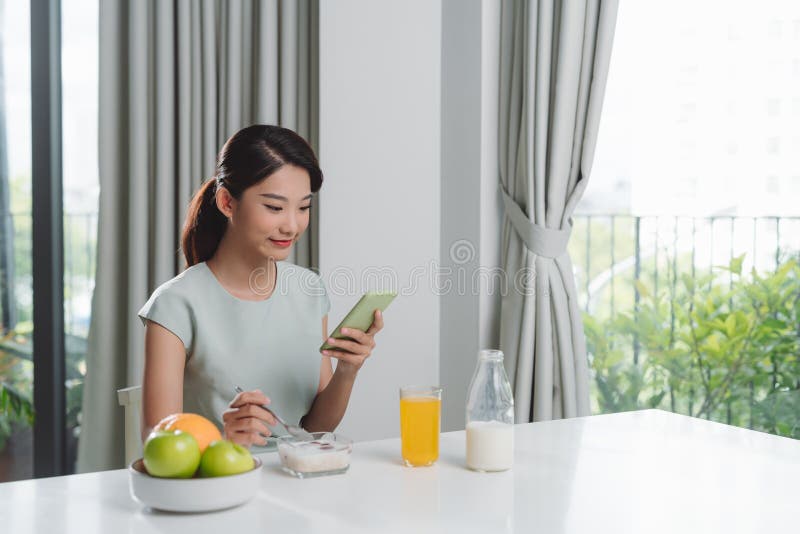 Woman Eating Breakfast Whilst Using Mobile Phone Stock Image - Image of ...