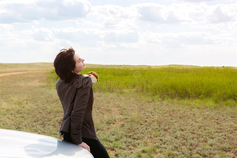 Woman Eating Burger while Standing Near the Car Stock Photo - Image of ...