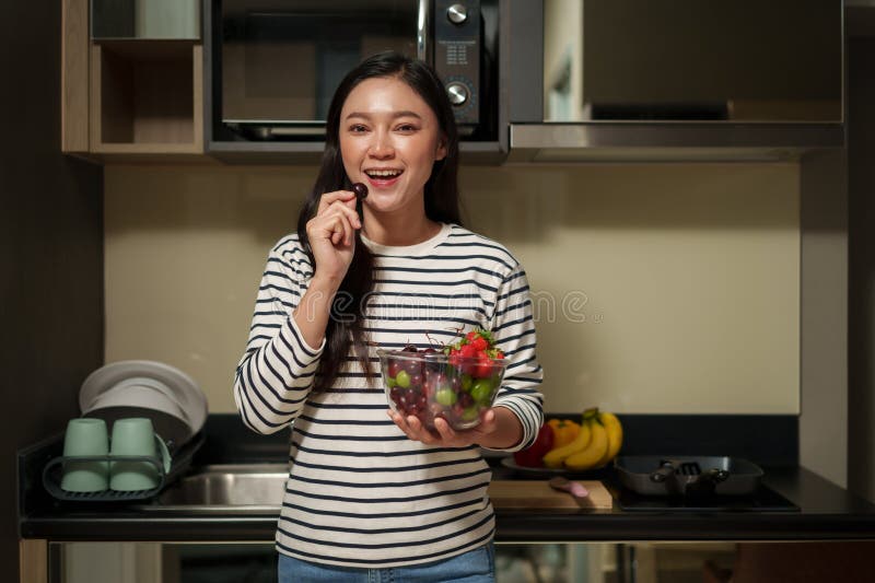 Woman Eating a Healthy Fruit in Home Kitchen Stock Photo - Image of ...