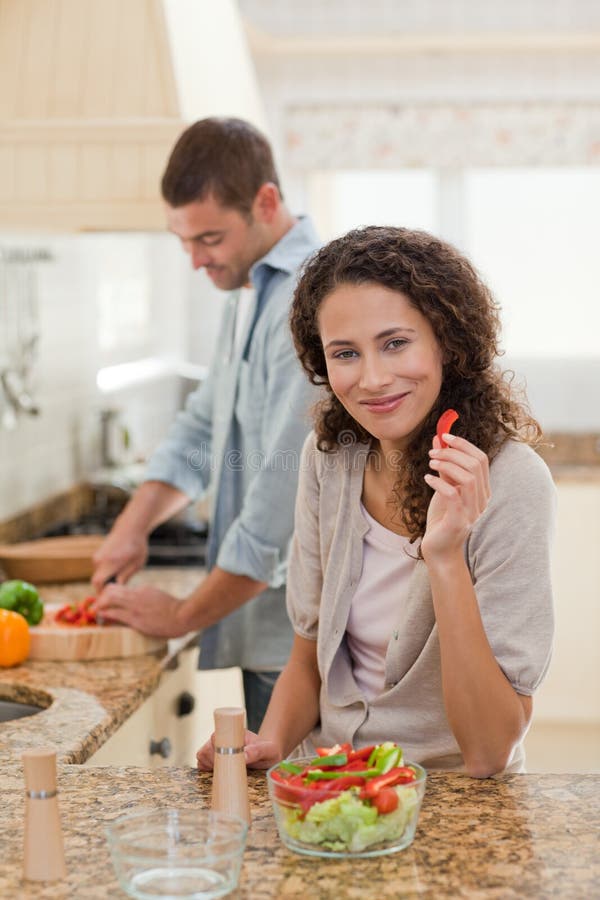 Woman Eating while Her Husband is Cooking Stock Photo - Image of pepper ...