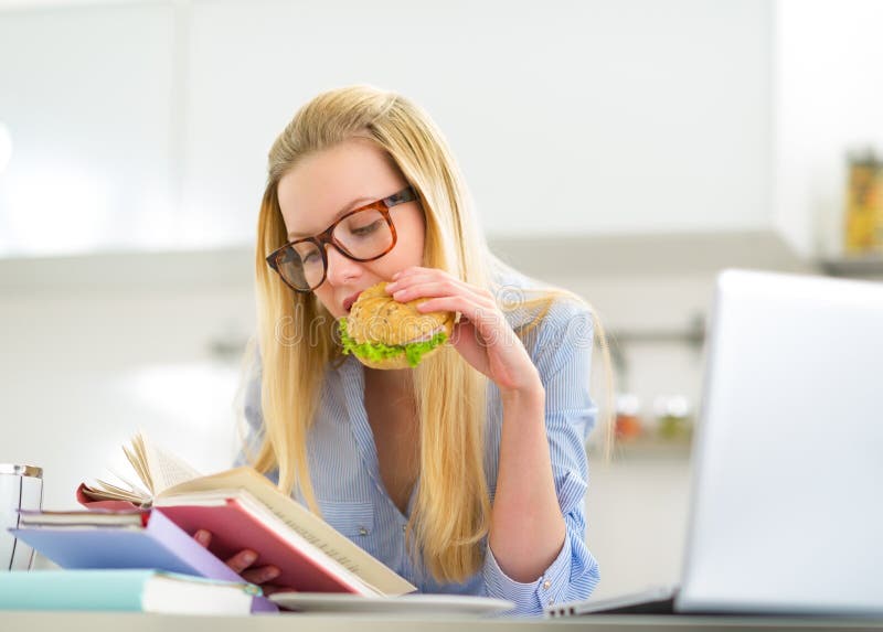 Woman Eating Sandwich while Studying in Kitchen Stock Image - Image of ...