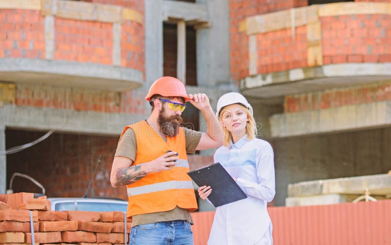 Woman Engineer and Builder Communicate at Construction Site. Discussing ...
