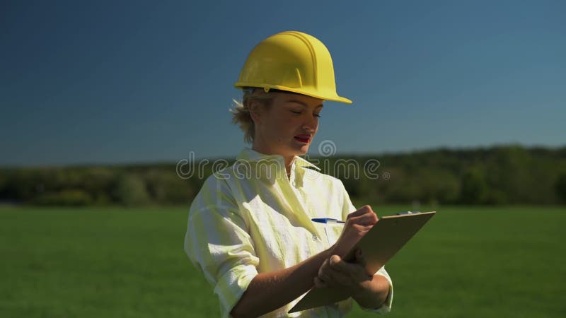 Woman Engineer in a Hard Hat is Writing Notes while Standing in the ...