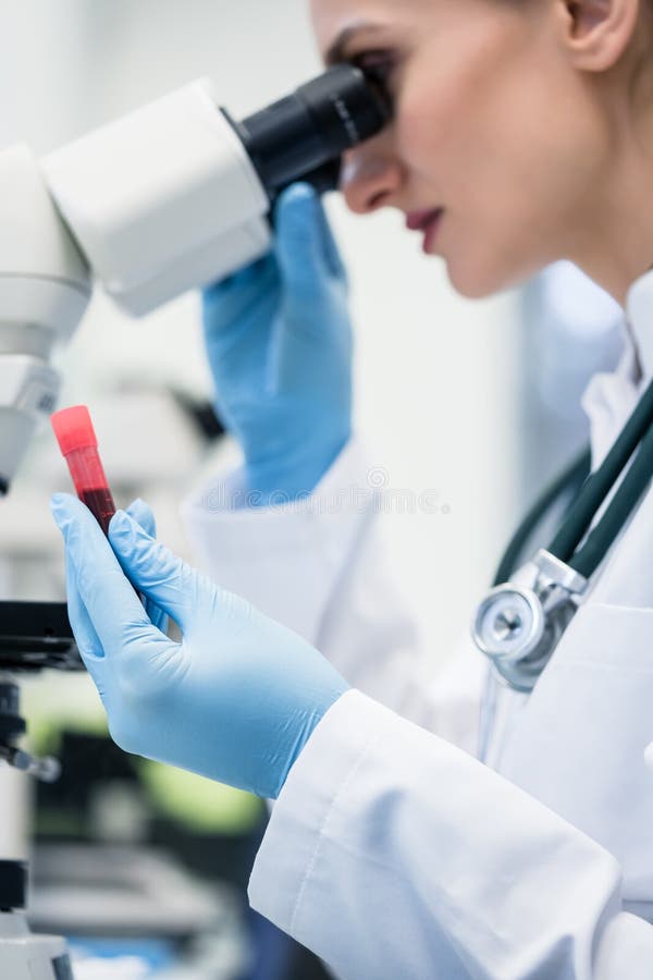 Woman Examining Blood Sample Under Microscope in Laboratory Stock Image ...