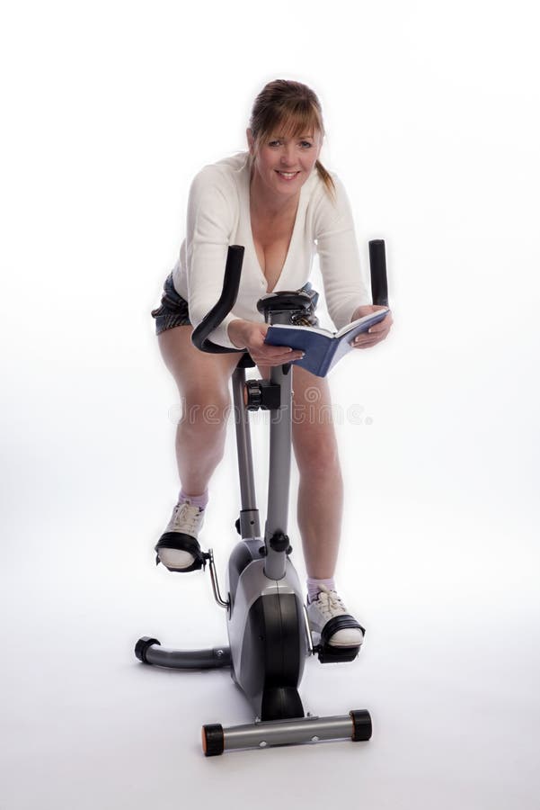 Woman on an Exercise Bike and Reading Stock Image - Image of middle ...