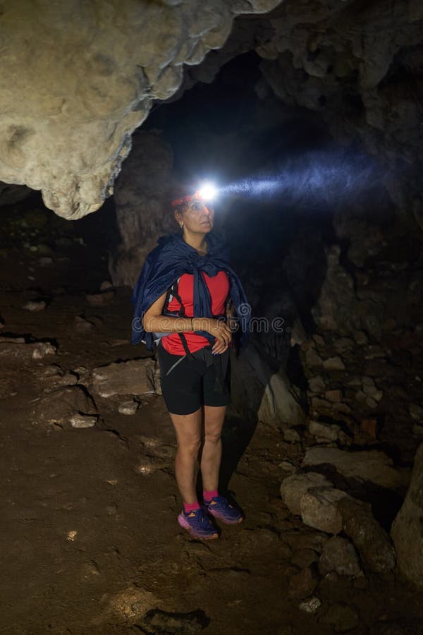 Woman exploring a cave stock image. Image of mineral - 335954415
