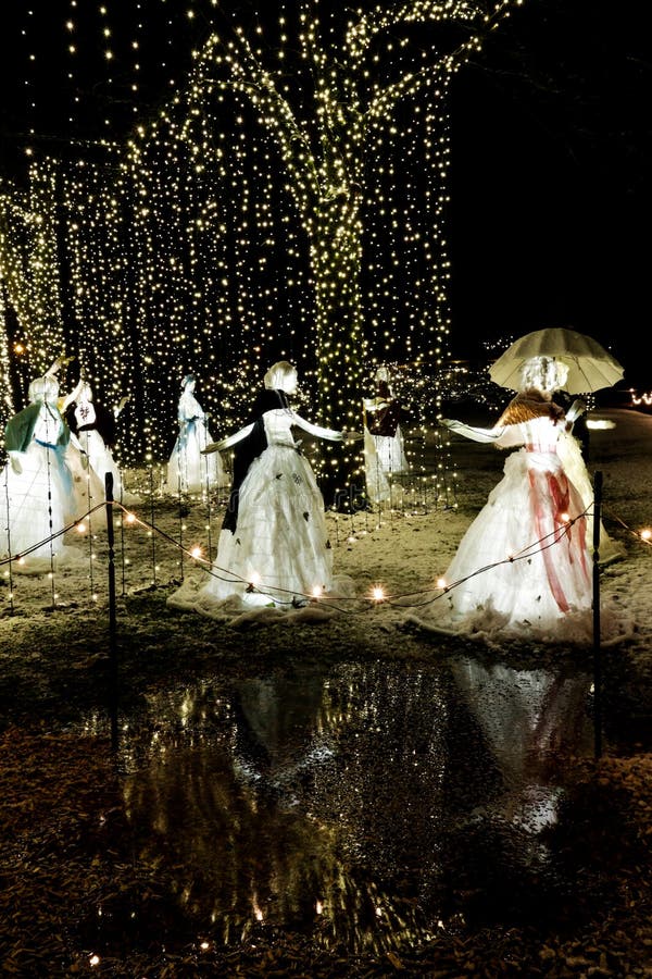 Woman Figures Dancing in White Dresses Under Bright String Lights on ...