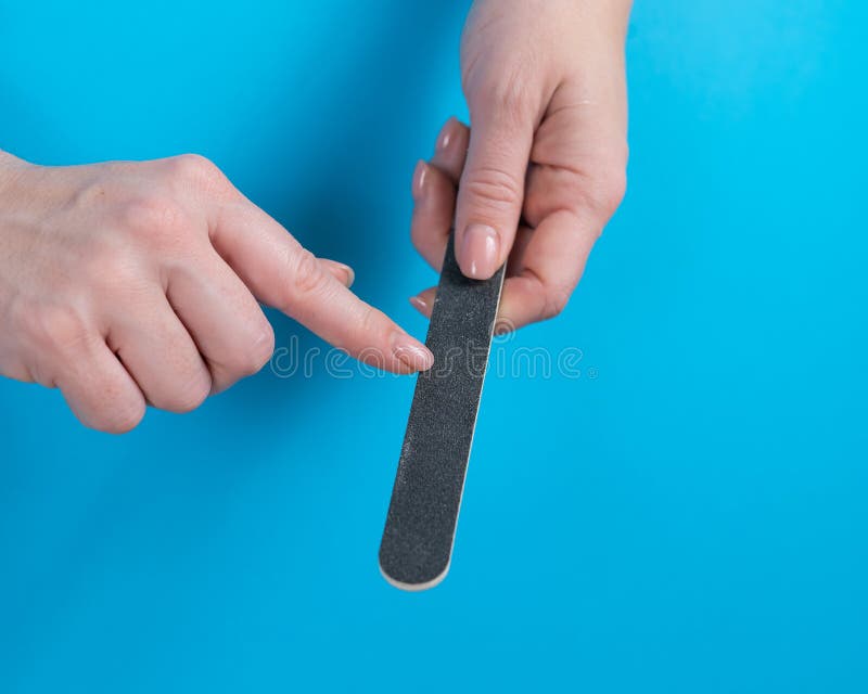 Woman Filing Her Nails on a Blue Background. Stock Image - Image of ...