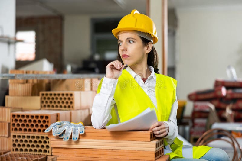 Woman Foreman in a Yellow Vest and a Protective Helmet Keeps Track of ...