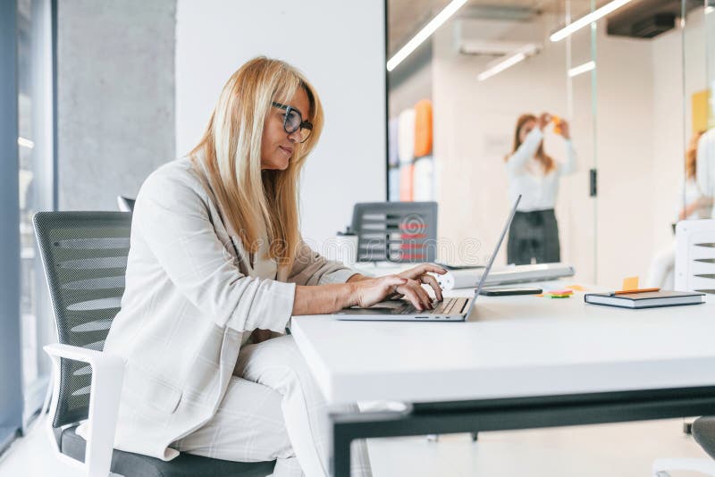 Woman in Formal Clothes Sitting in the Office and Working by Using ...