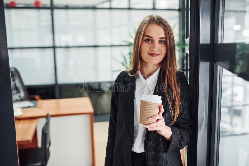 Woman in Formal Clothes Standing Indoors in the Office with Cup of ...