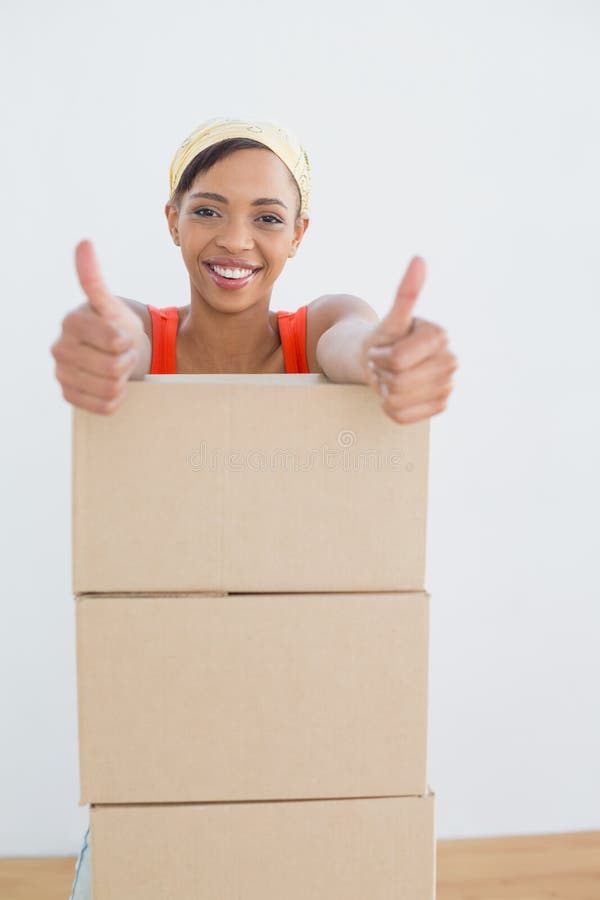 Woman Gesturing Thumbs Up with Stack of Boxes in a New House Stock ...