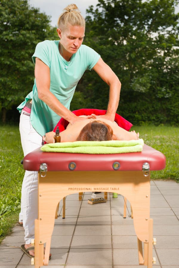 Woman Getting Massage On Table Outdoor In Garden From Masseur Stock