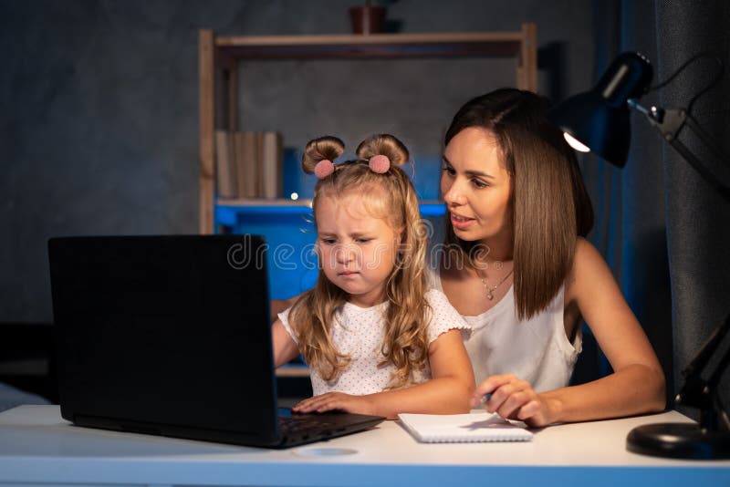 Woman with Girl Doing Homework on Laptop in the Evening. Little Girl ...