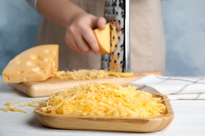 Woman Grating Cheese at Table, Focus on Plate Stock Image - Image of ...