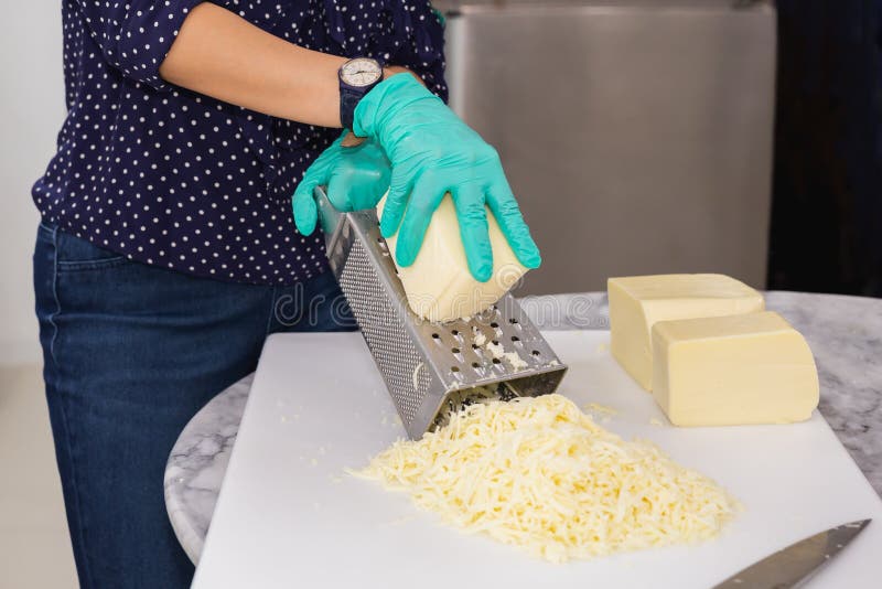 Woman with Green Gloves Grating Cheese on Kitchen Table. Stock Image ...