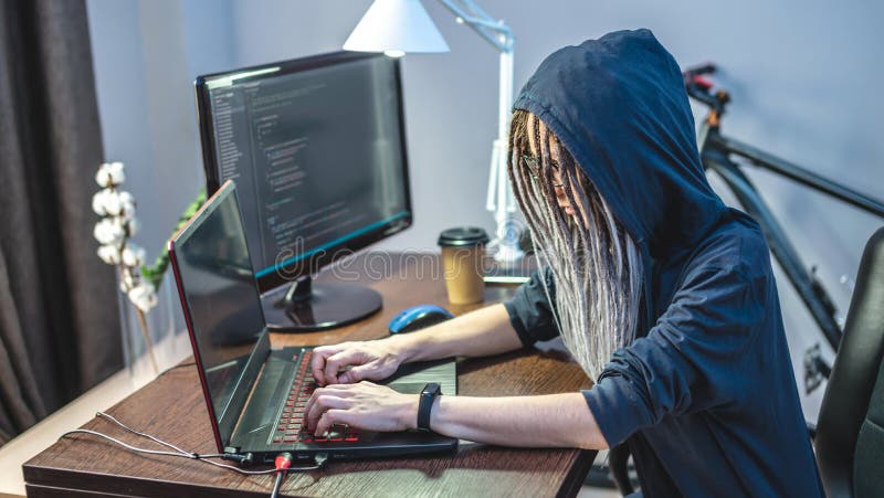 Hacker In A Hood Are Programming Virus Code On A Laptop The Concept Of Internet Fraud And