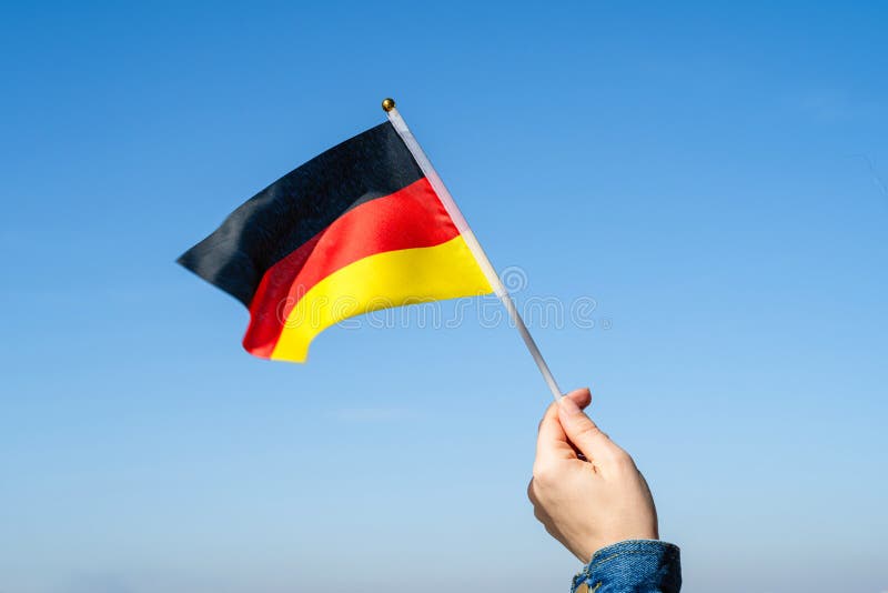 Woman Hand with Germany Swaying Flag on the Blue Sky. Concept. Stock ...
