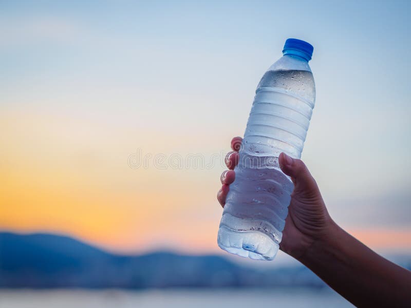 Woman Hand Holding Water Bottle on Sunset Sky Background. Stock Photo ...