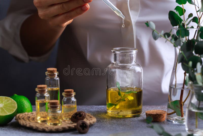 Woman Hand Pouring Eucalyptus Essential Oil into Bottle on Grey Table ...