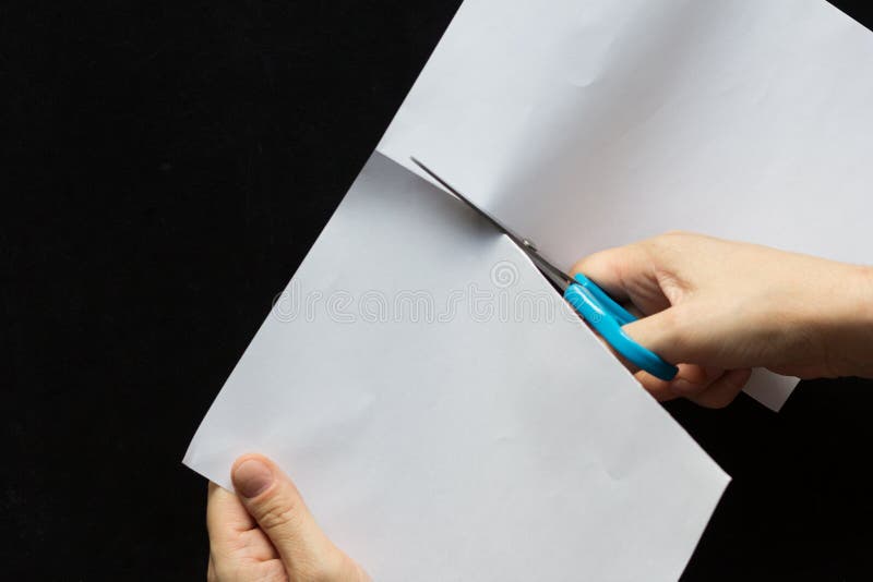 Woman Hands Cutting Rectangular Sheet of Paper in Half on the Black ...