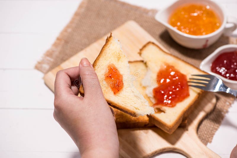 Woman Hands Eating Bread with Strawberry Jam for Breakfast. Focus on ...