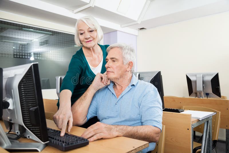 Woman Helping Male Classmate in Computer Lab Stock Photo - Image of ...