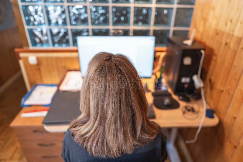Woman with Her Back Turned Working from Home at Her Workstation with ...
