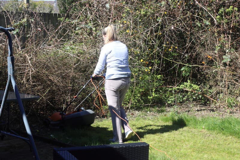 A Woman In Her Garden Mowing Her Lawn During A Sunny Afternoon Stock Image Image Of Mowing