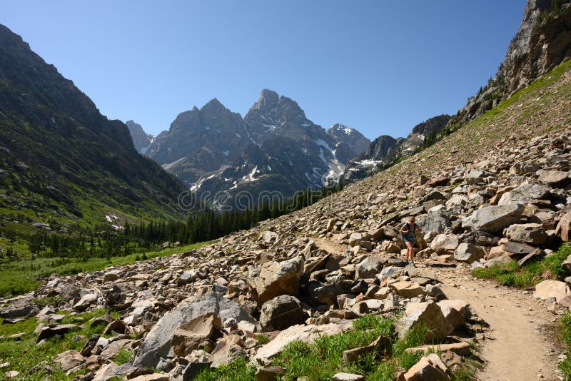 Woman Hikes through Boulder Field with Tetons Stock Photo - Image of ...