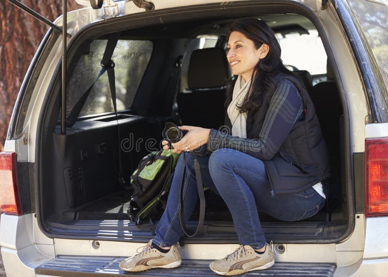 Woman Holding Camera Sits in the Open Back of a Car Stock Photo - Image ...