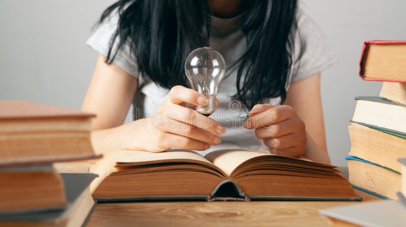 Woman Holding a Light Bulb in Front of a Book in the Library Stock ...