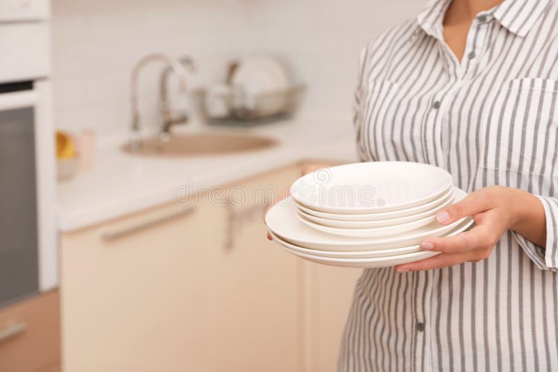 Woman Holding Stack of Clean Dishes in Kitchen. Stock Photo - Image of ...