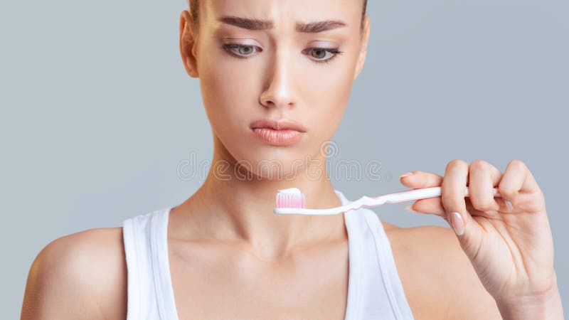 Woman Holding Toothbrush with Toothpaste, Unsure Expression, Close-Up ...