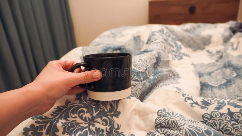 A Woman Holds a Green Mug on a Green Patterned Duvet Cover in the Bed ...