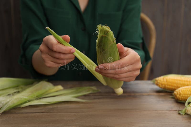 Woman Husking Corn Cob at White Wooden Table, Closeup Stock Image ...