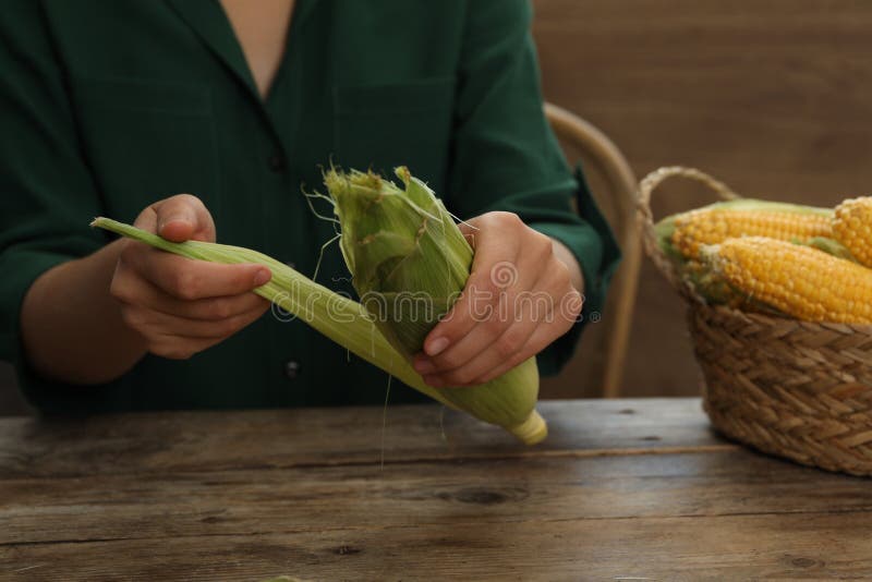Woman Husking Corn Cob at Wooden Table, Closeup Stock Image - Image of ...