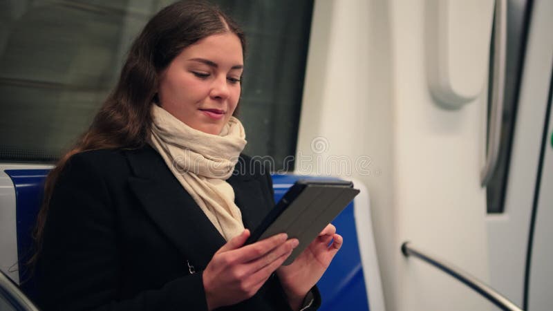 Woman Comfortably Reading on an E-reader while Sitting on a Subway ...