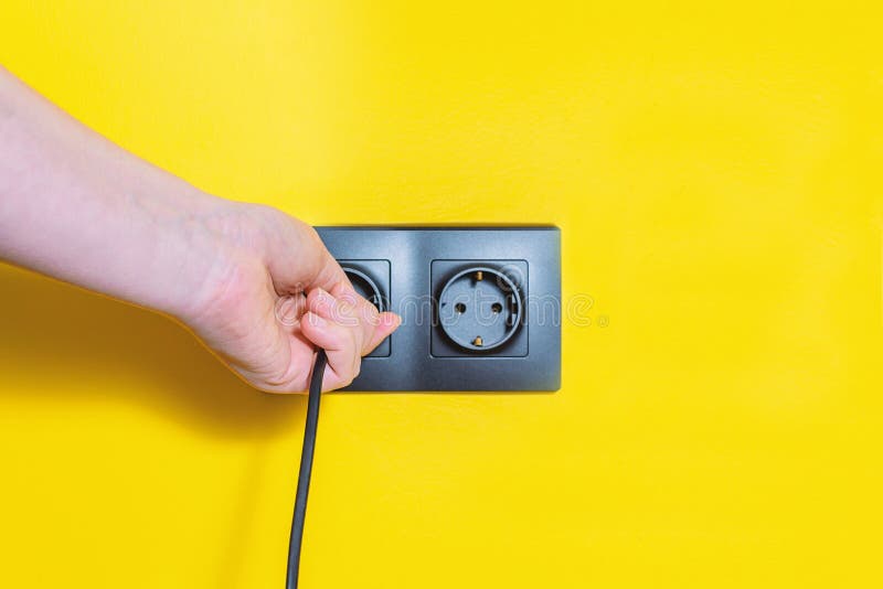 Woman Input Electric Plug. Yellow Wall Background. Stock Photo - Image ...
