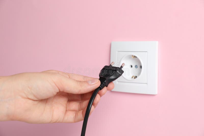 Woman Inserting Plug into Power Socket on Pink Wall, Closeup ...