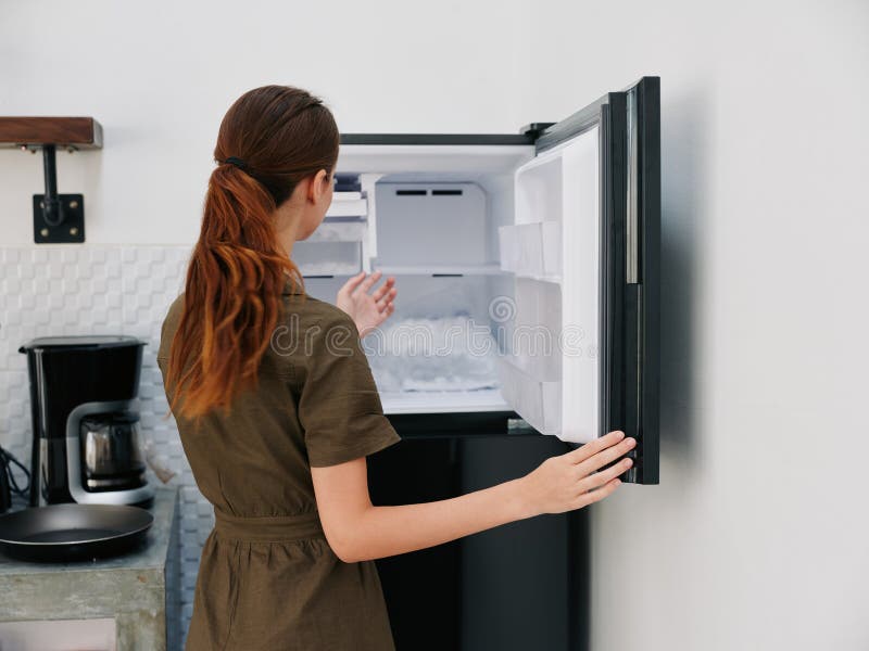 A Woman in the Kitchen of Her Home Opened an Empty Freezer with Ice ...