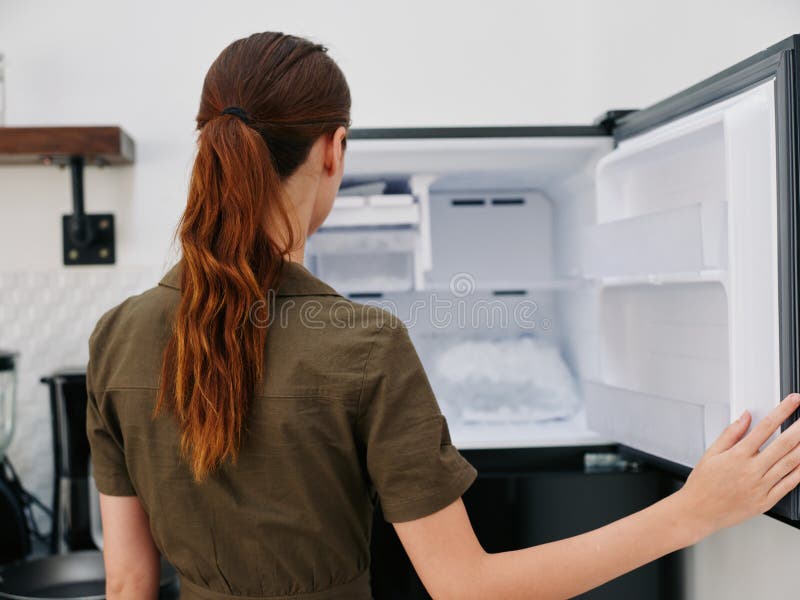 A Woman in the Kitchen of Her Home Opened an Empty Freezer with Ice ...