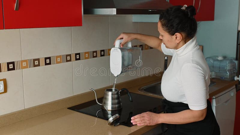 Woman Preparing Boiling Water in a Modern Kitchen with Red Cabinets ...