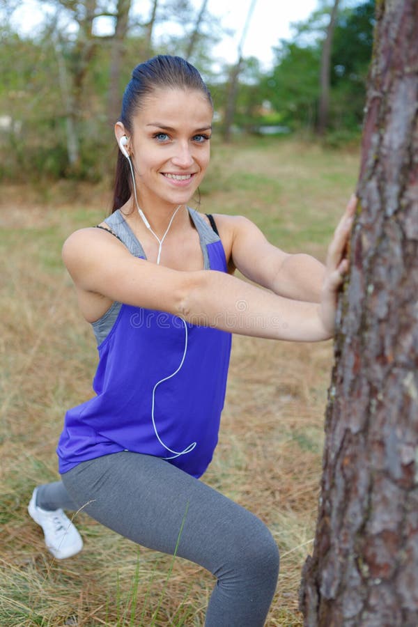 Woman Leaning Against Tree To Stretch Leg Muscles Stock Photo - Image ...