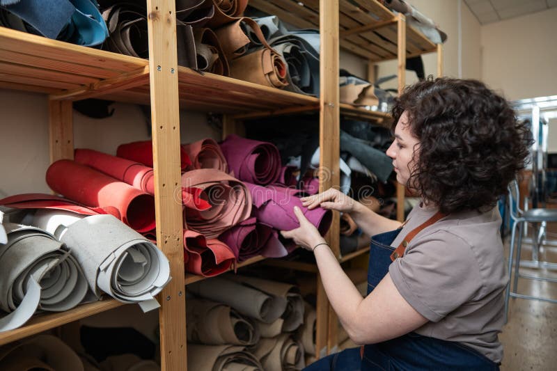 Woman Leatherworker Selects a Roll of Leather in the Workshop. Stock ...