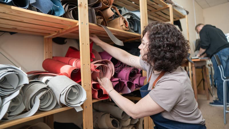 Woman Leatherworker Selects a Roll of Leather in the Workshop. Stock ...
